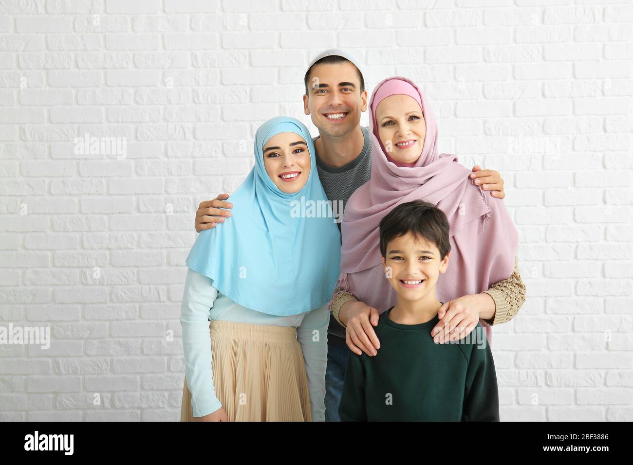 Portrait of Muslim family on white brick background Stock Photo - Alamy
