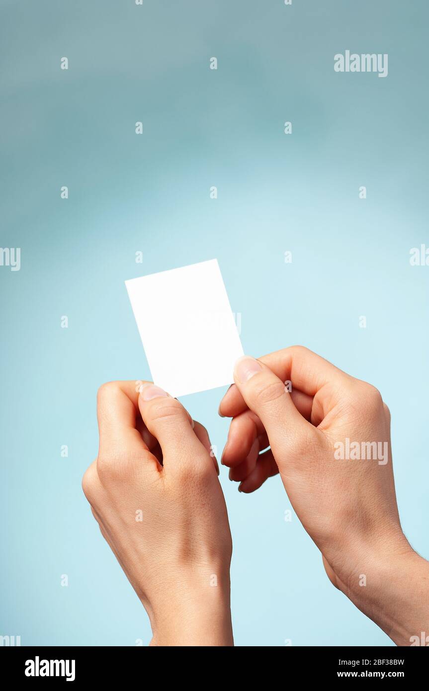 Woman holding small blank white note paper with two hands, vertical ...