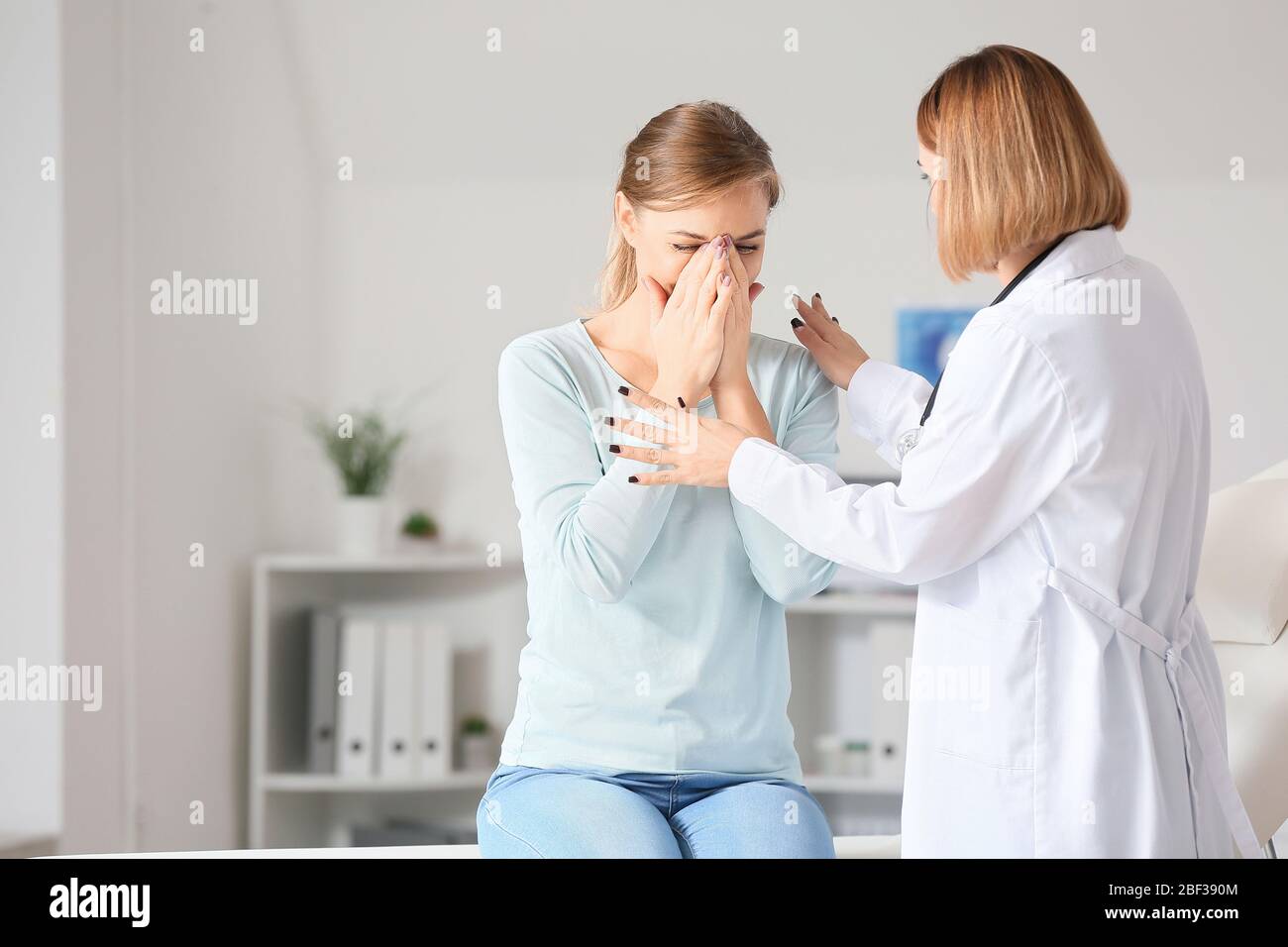 Female doctor calming sad patient in clinic Stock Photo - Alamy
