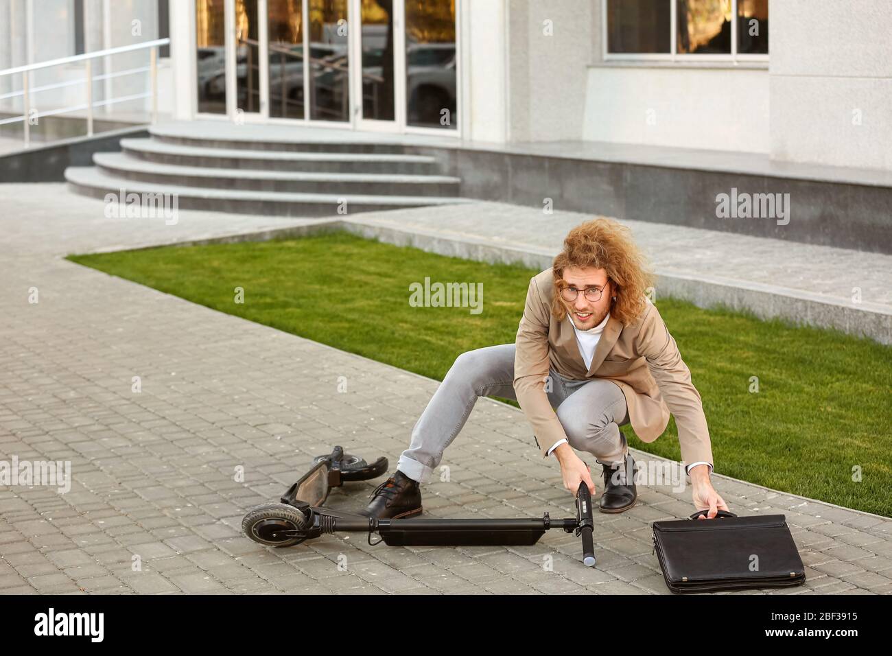 Young man fallen off his kick scooter outdoors Stock Photo - Alamy