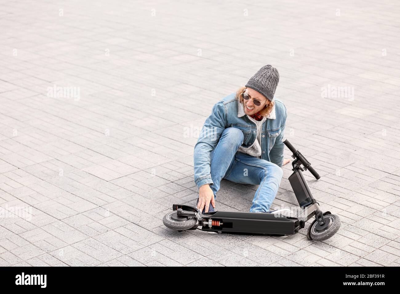 Young man fallen off his kick scooter outdoors Stock Photo - Alamy