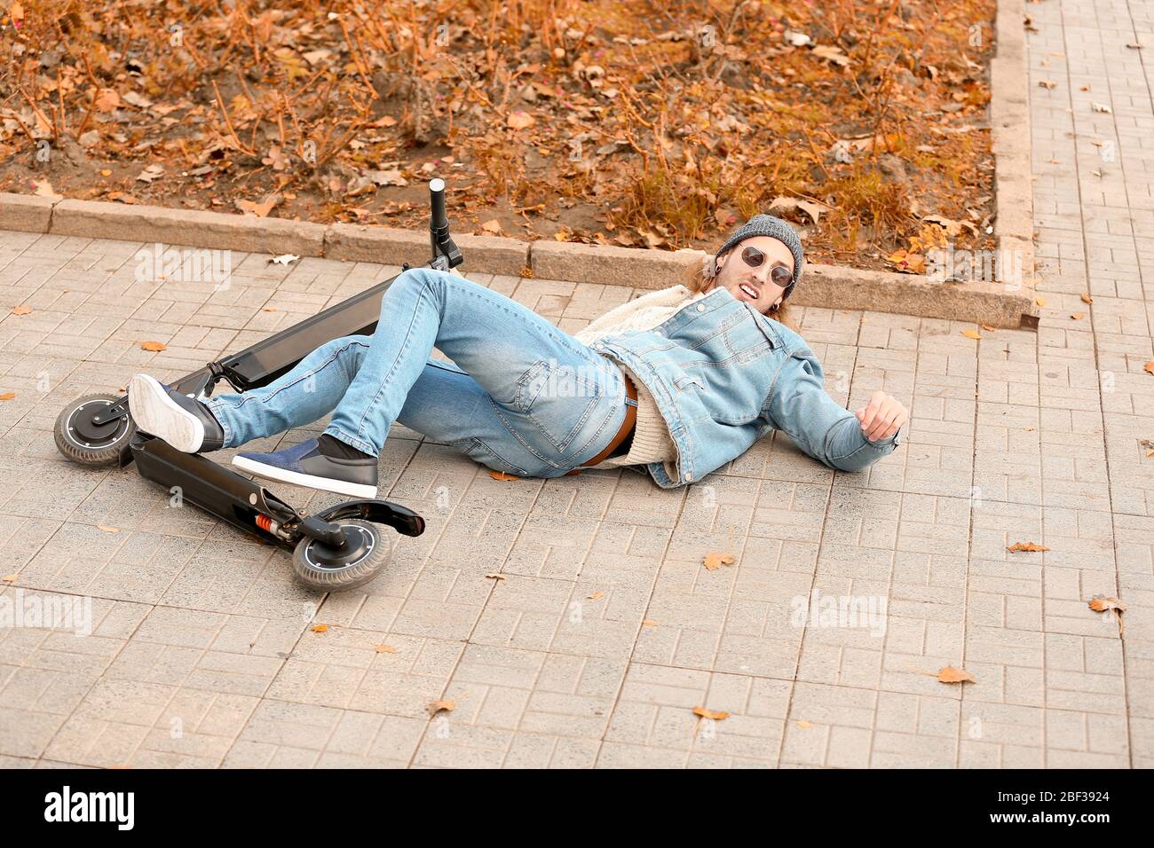 Young man fallen off his kick scooter outdoors Stock Photo - Alamy