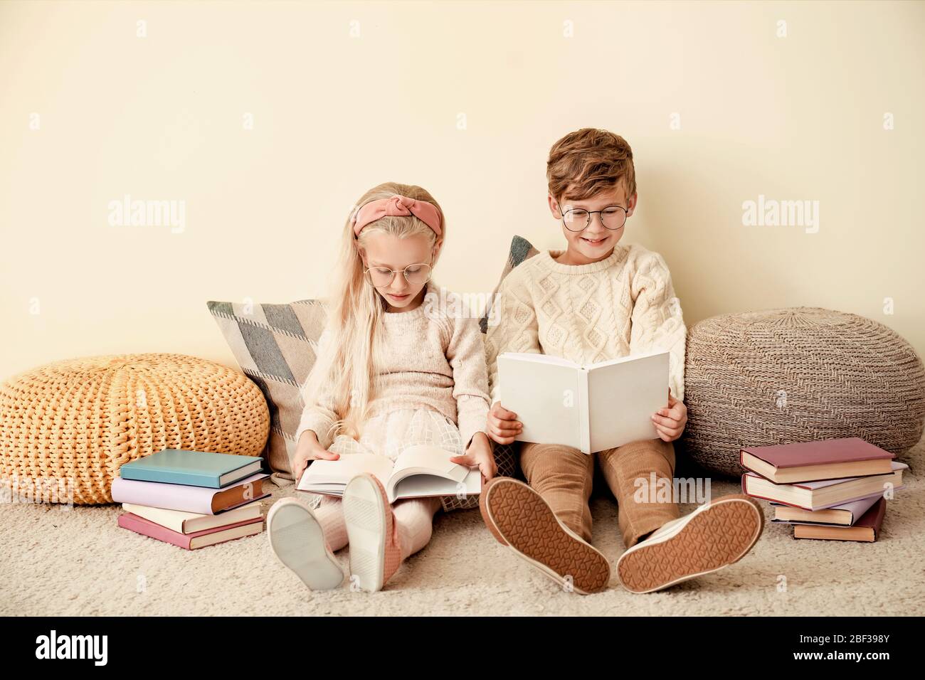 Little children reading books near color wall Stock Photo - Alamy
