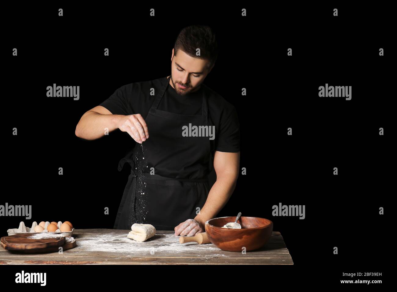 Man sprinkling dough with flour in kitchen Stock Photo - Alamy