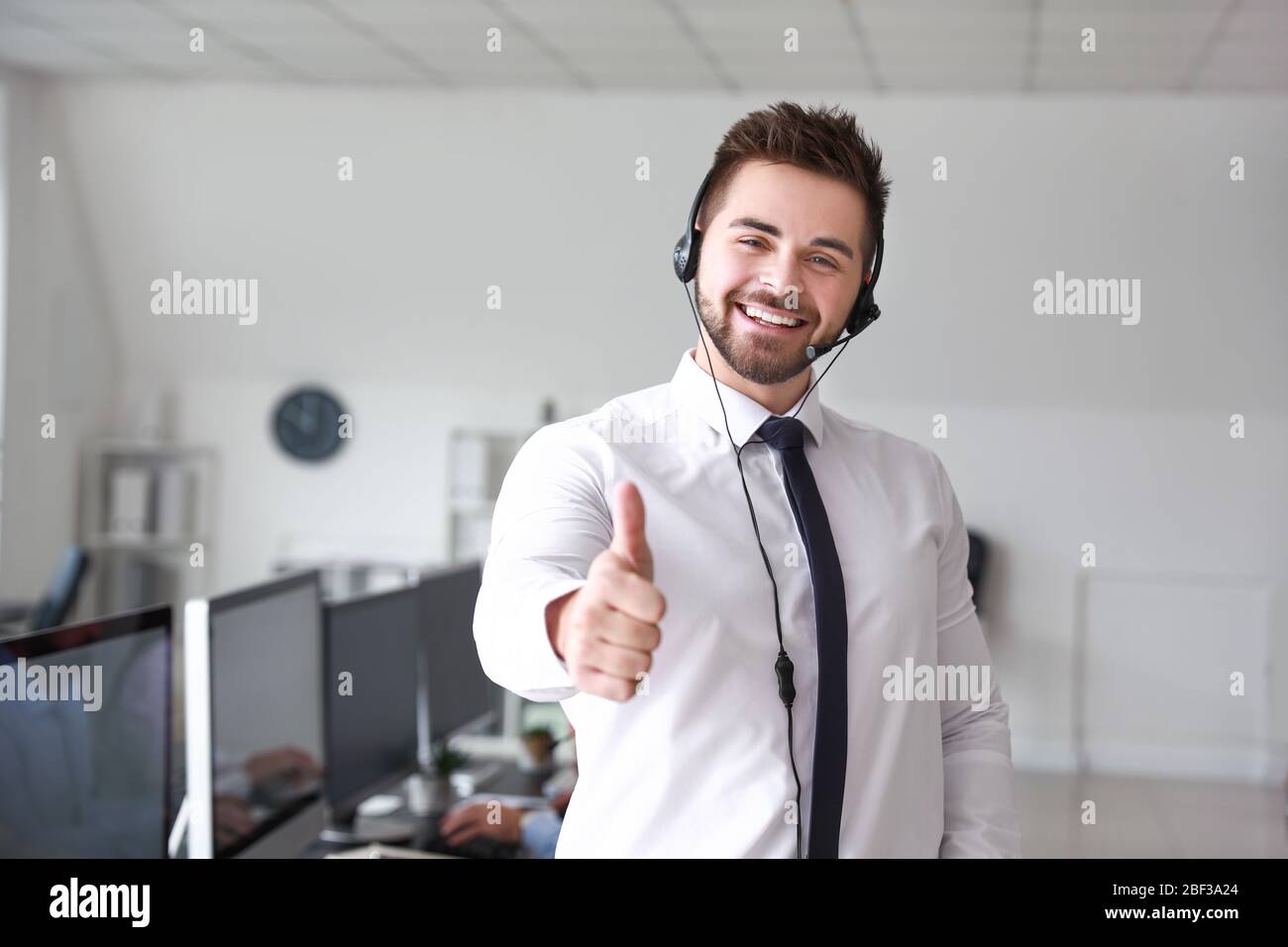 Portrait of male technical support agent showing thumb-up in office ...