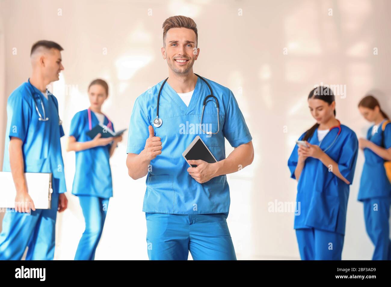 Male medical student showing thumb-up gesture in hall of clinic Stock ...