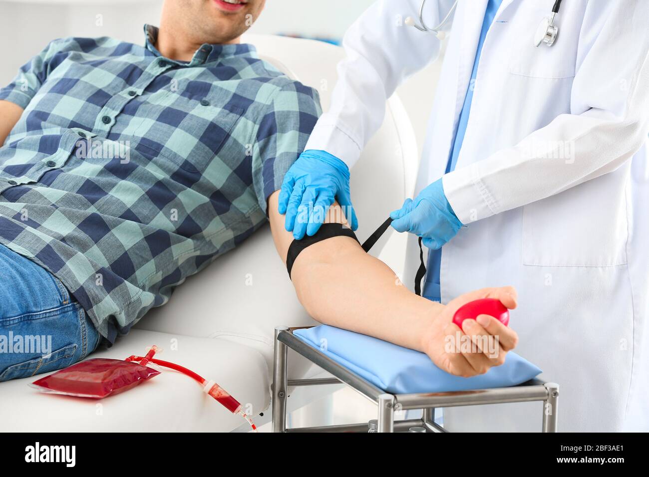 Female doctor preparing male donor for blood transfusion in hospital ...