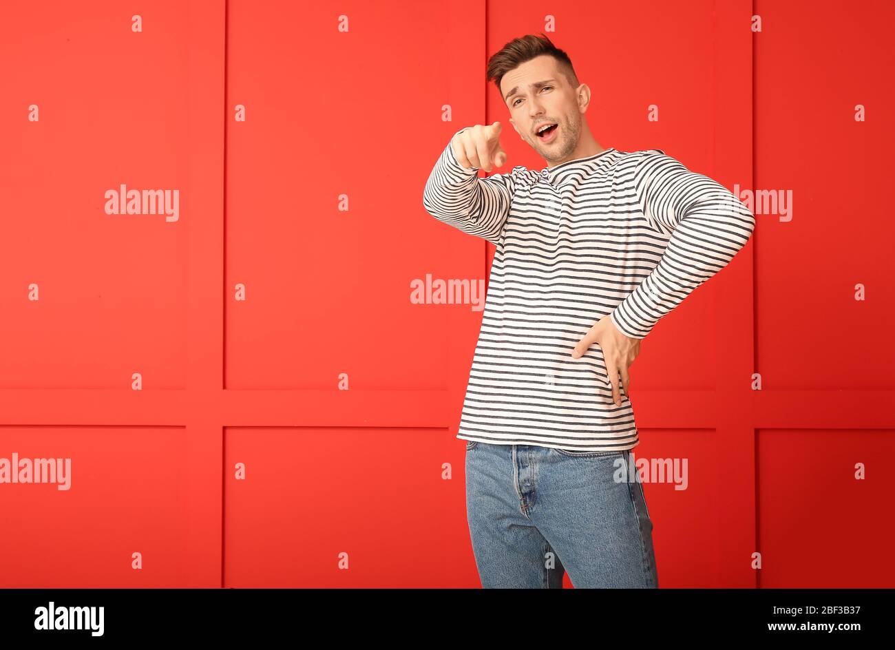 Happy man pointing at viewer on color background Stock Photo - Alamy