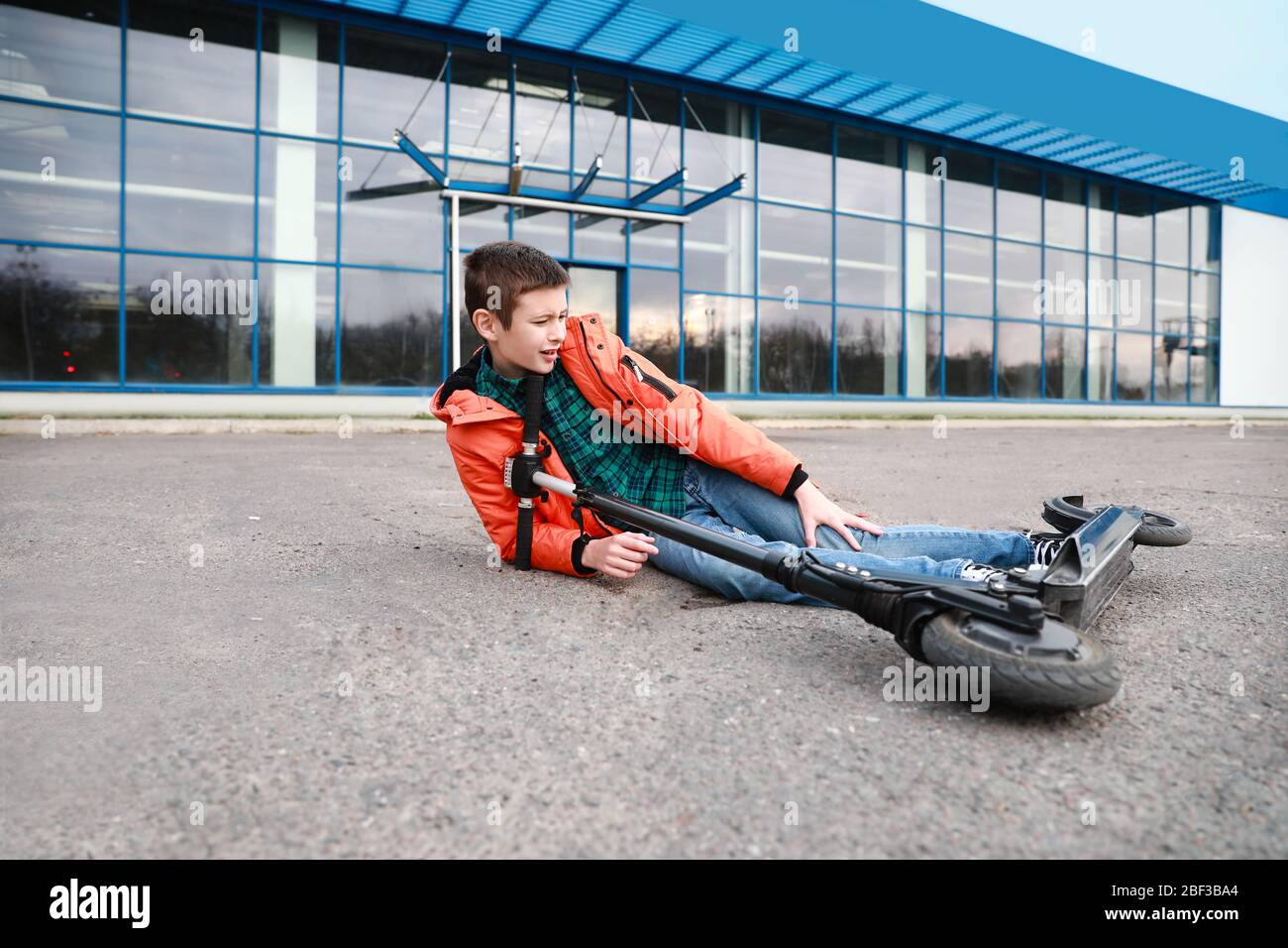 Teenage boy fallen off his kick scooter outdoors Stock Photo - Alamy