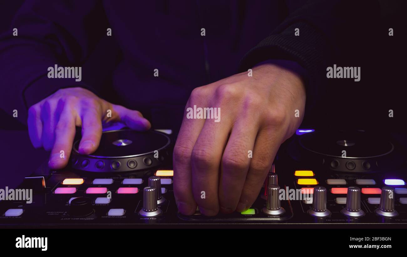 DJ plays music. sound mixer controller with knobs and sliders close up ...