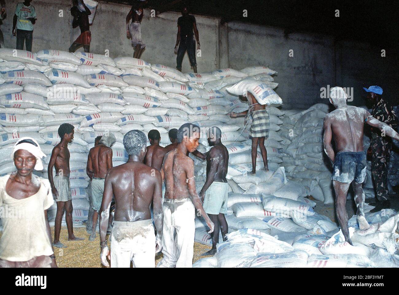 1993 - Somali men work in a food storage warehouse in Kismayo. The ...