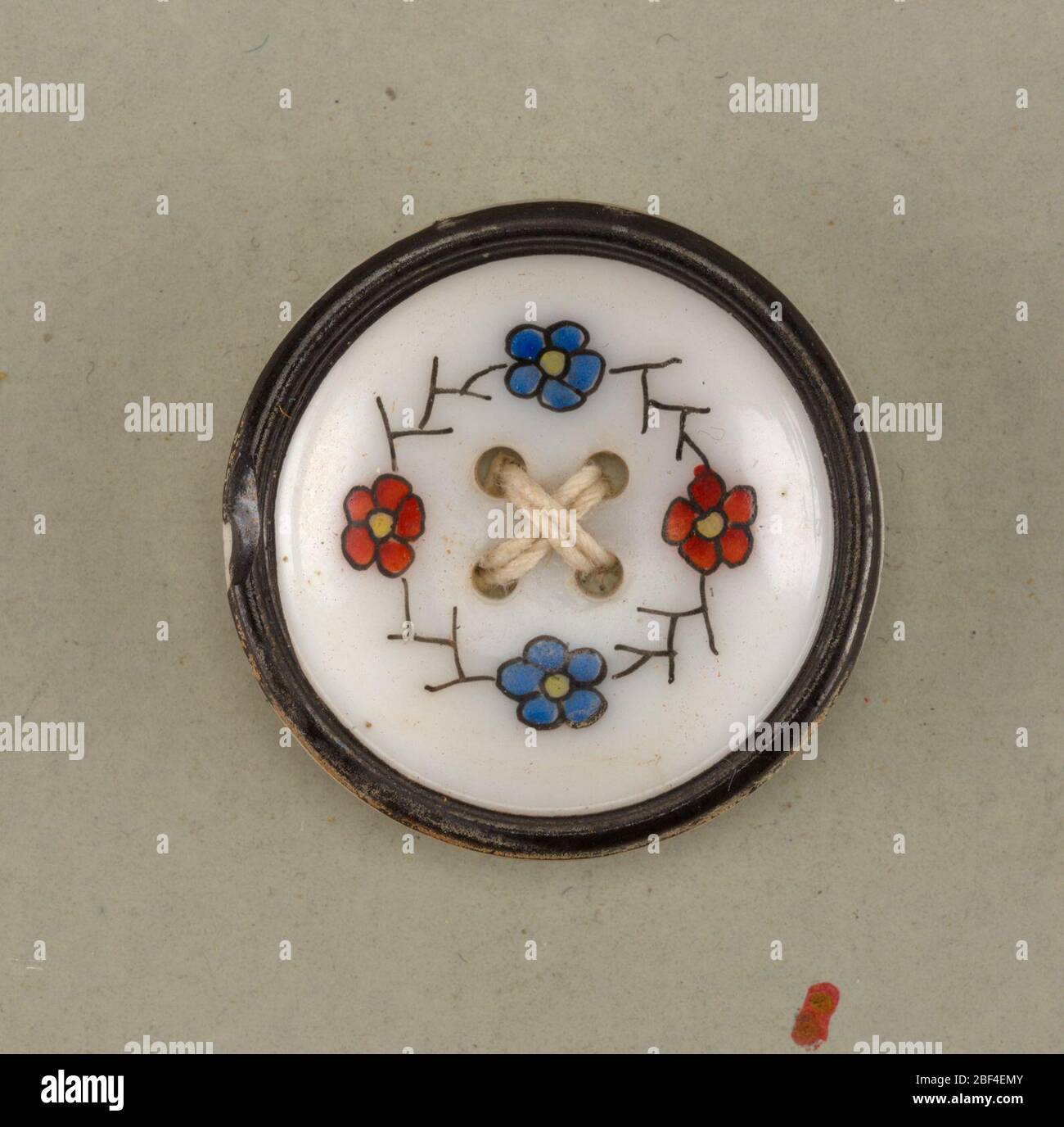 Button. concave button ornamented with four small flowers [two red and ...