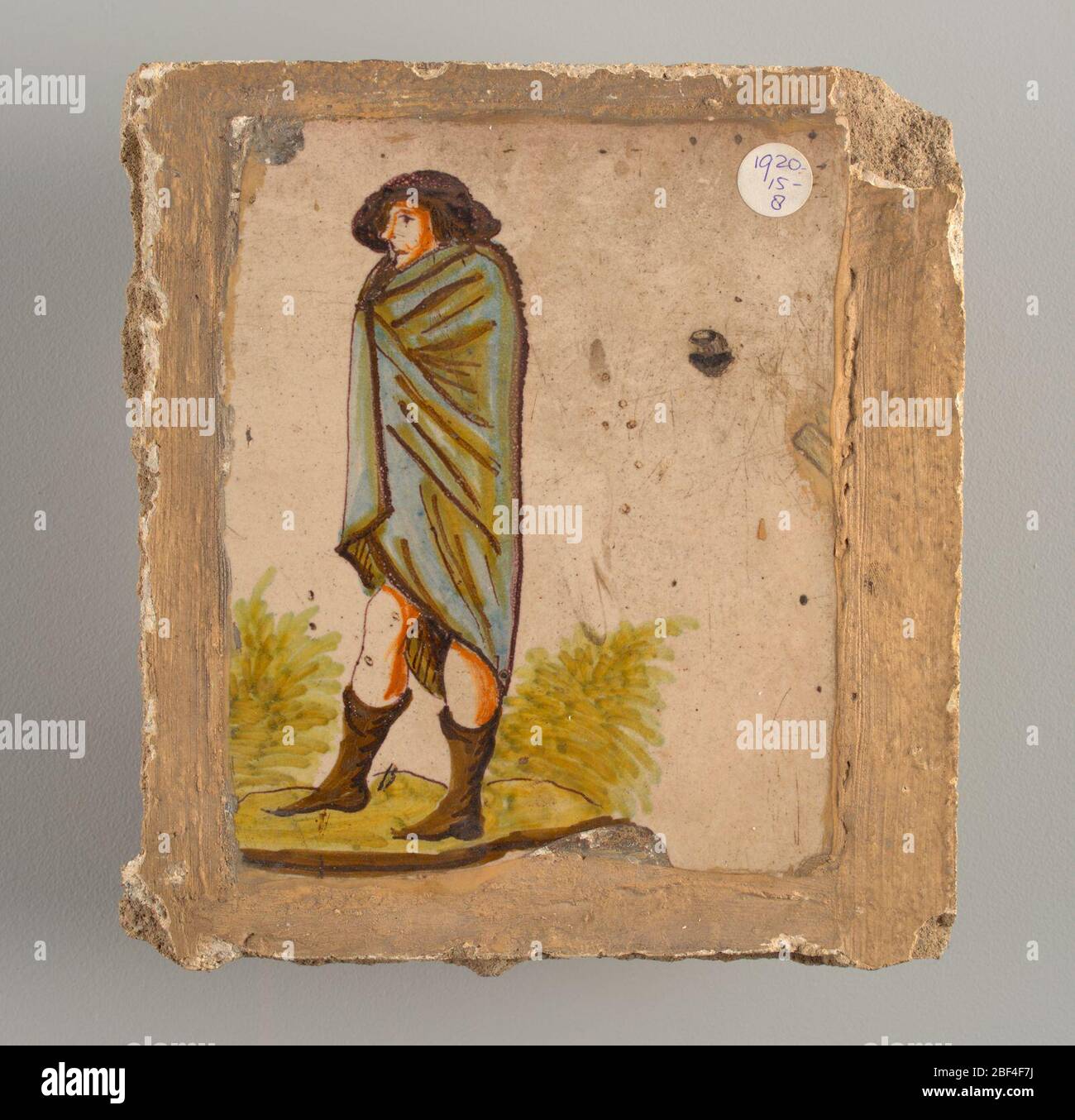 Tile. Man standing, turned toward left, wrapped in bluish cloak and ...