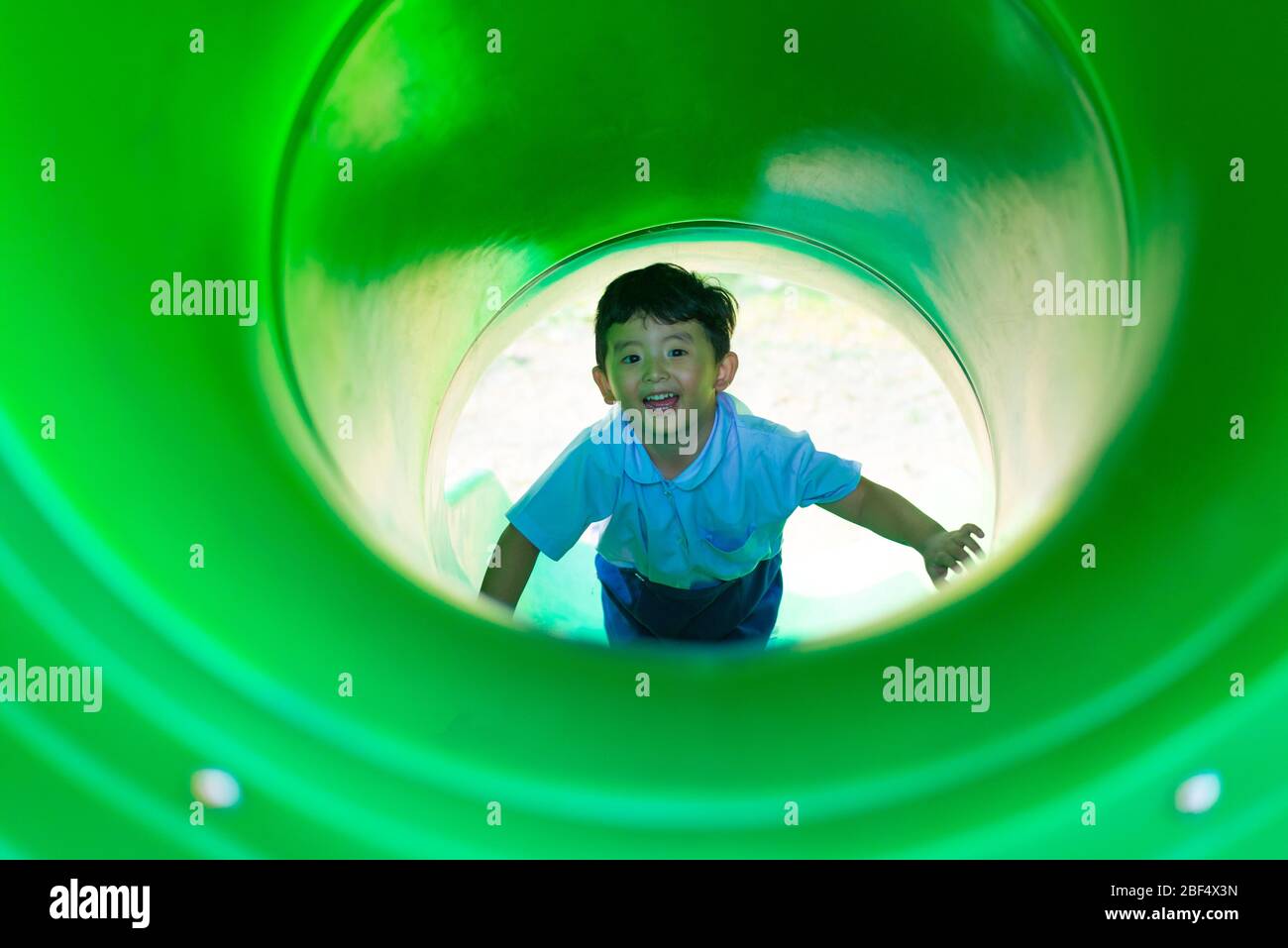 Little Asian kid climbing up the slide at the playground under the ...