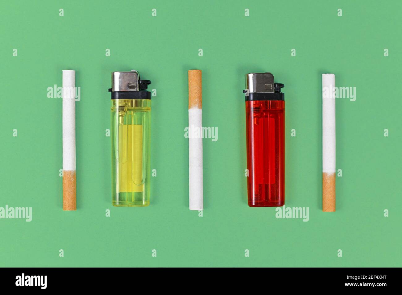 Flat lay with cigarettes and plastic lighters in a row on green ...