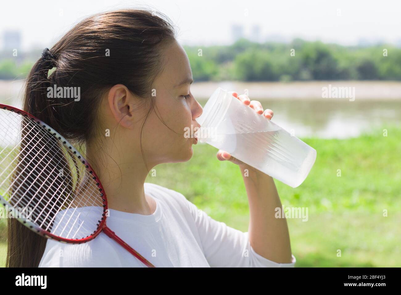 A badminton drinking water during practice at the park on a hot day ...