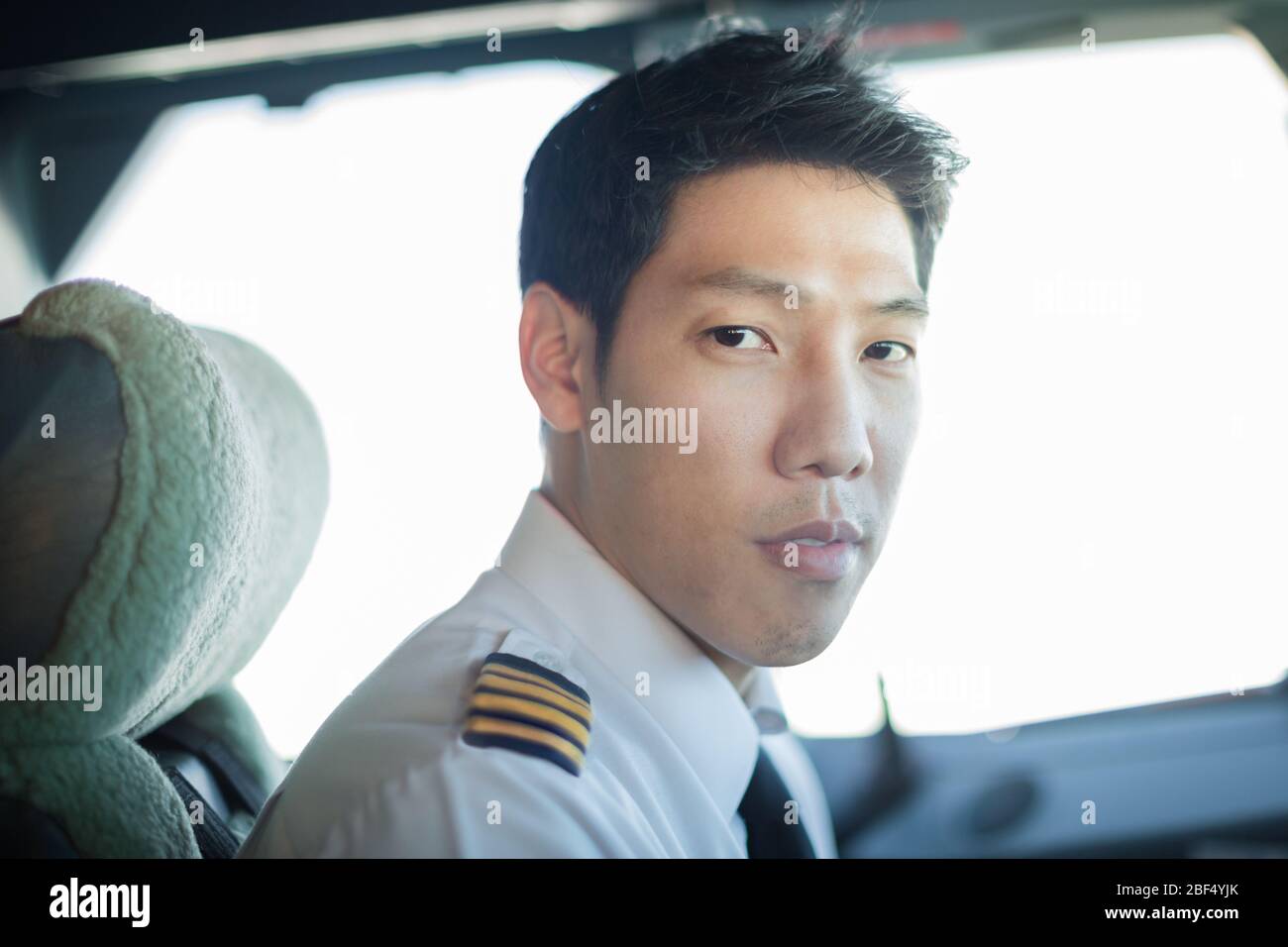 Asian male pilot sitting in the cockpit looking into the camera ...