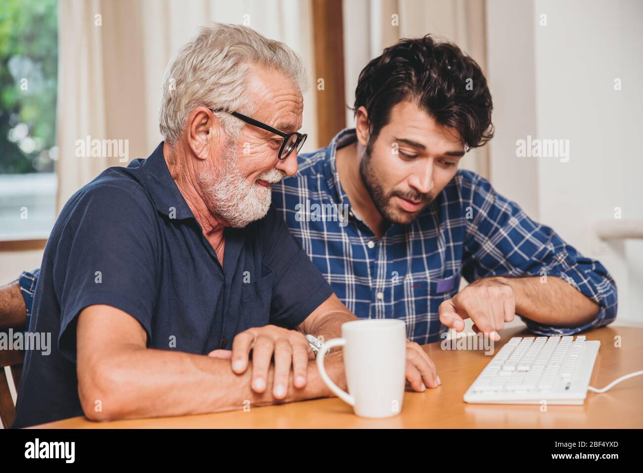 young man or son teaching his grandfathe elderly dad learning to using ...