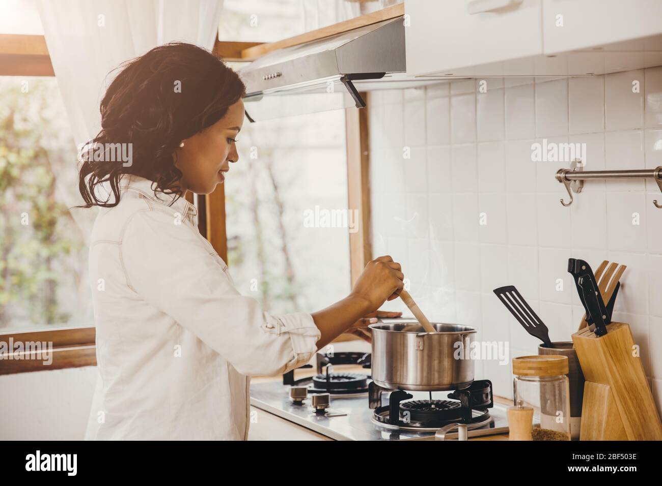 African American Black woman cooking boiling soup in the kitchen at ...
