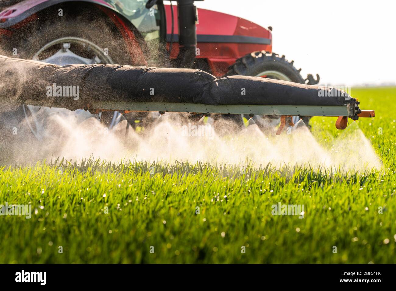 Tractor spraying pesticides over a green field Stock Photo - Alamy