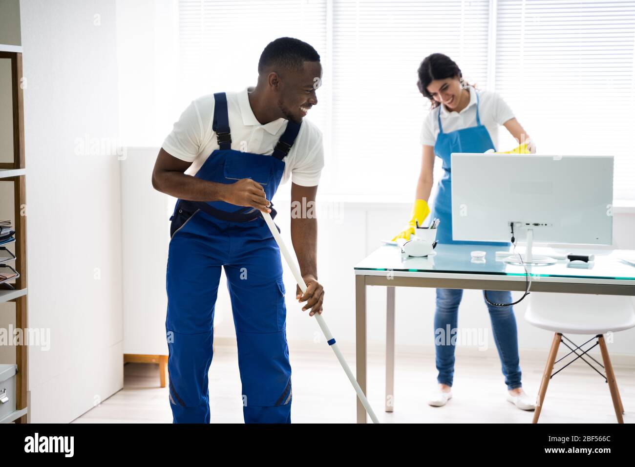 Young Male And Female Cleaners Cleaning Office Stock Photo - Alamy