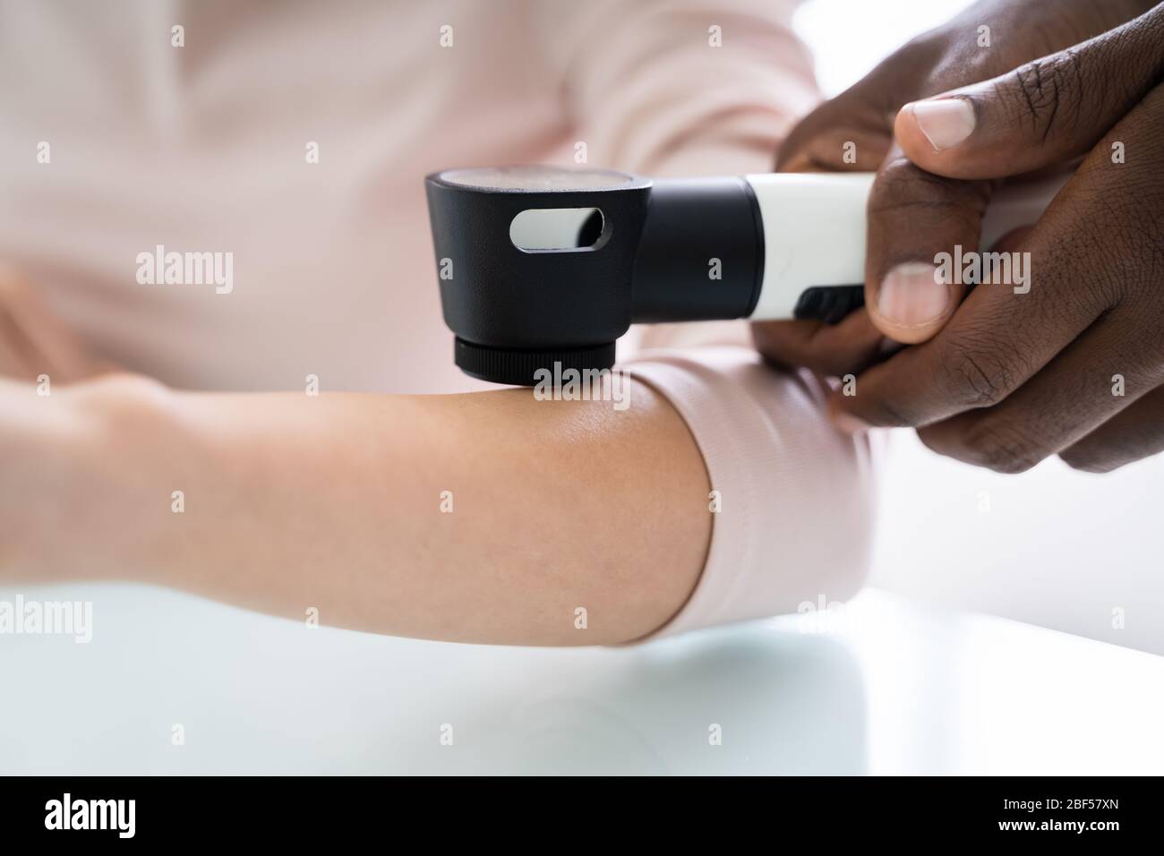 Female Doctor Examining Skin Of Female Patient With Dermatoscope In ...