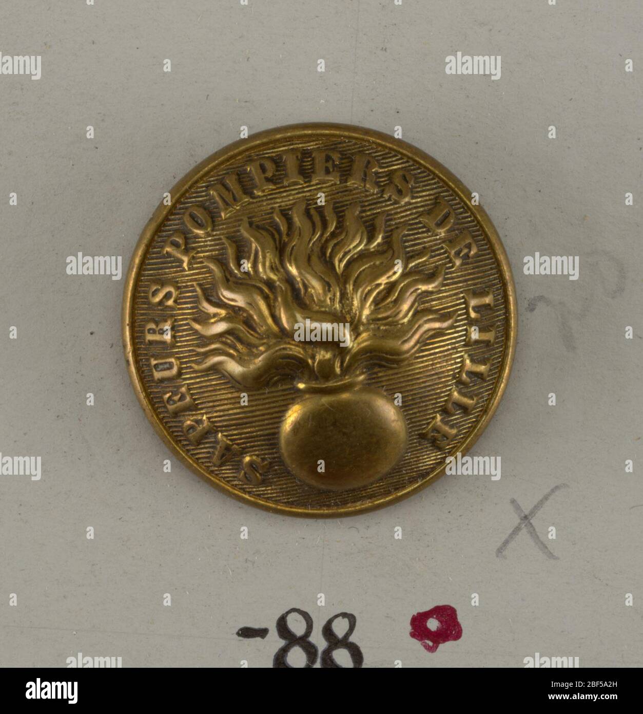 Button. Convex button with ornament of a flaming bomb shown on lined ...
