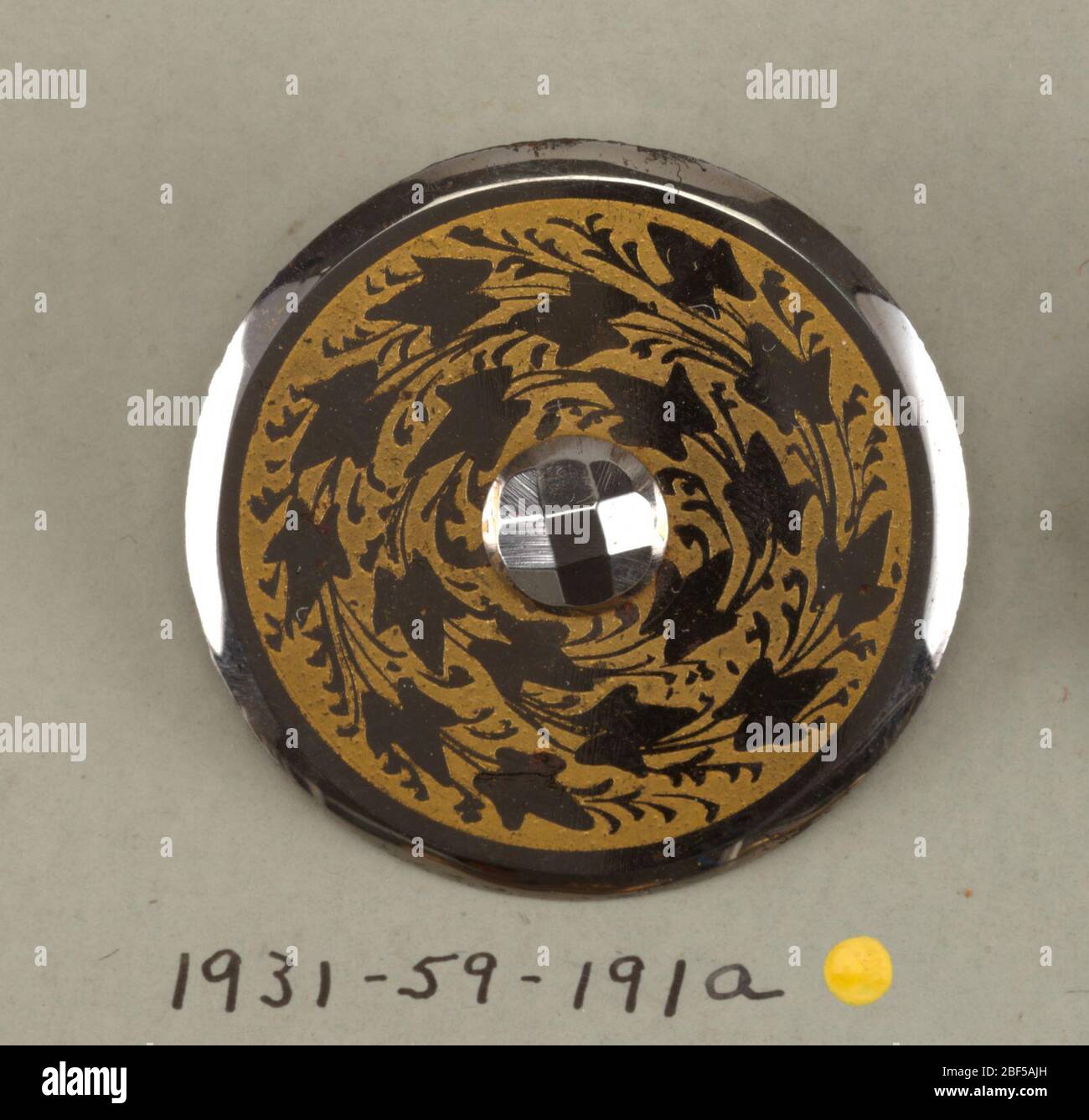 Button. Flat, circular button with beveled edges; in the center, a ...