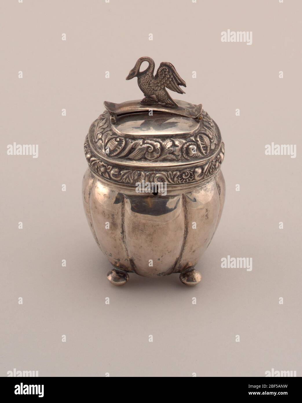 Coin bank. Coin bank with lobed body on ball feet. Lid with floral ...