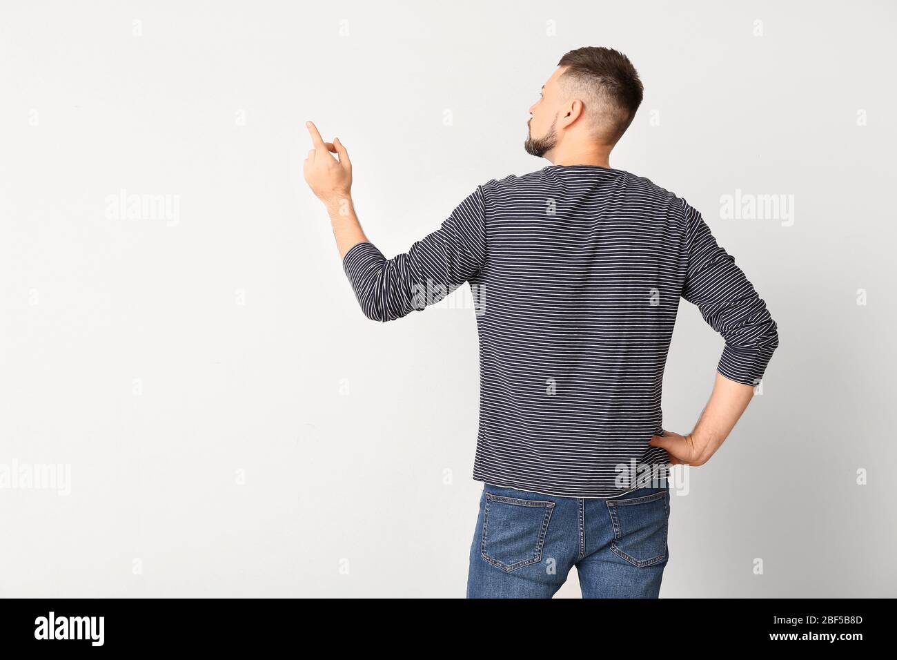 Man pointing at something on light background Stock Photo - Alamy