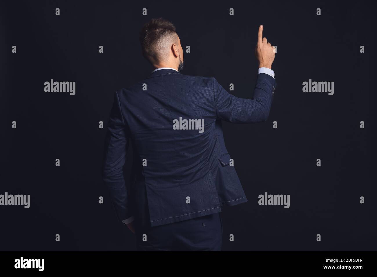 Businessman pointing at something on dark background. Concept of choice ...