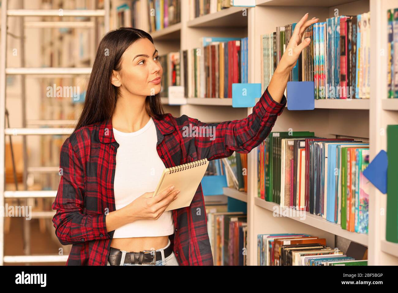 Young female student choosing book in library Stock Photo - Alamy
