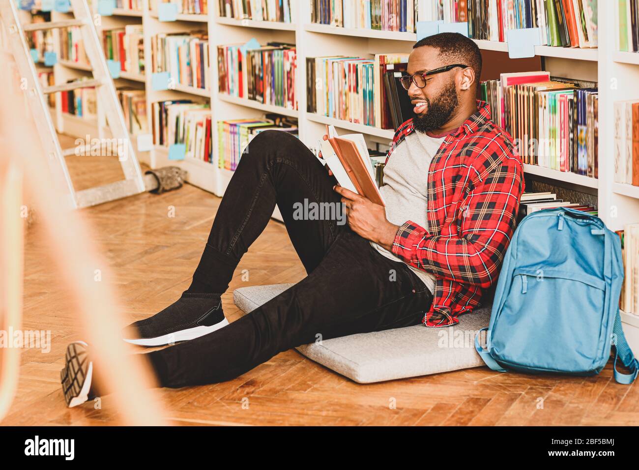 African-American student reading book while preparing for exam in ...