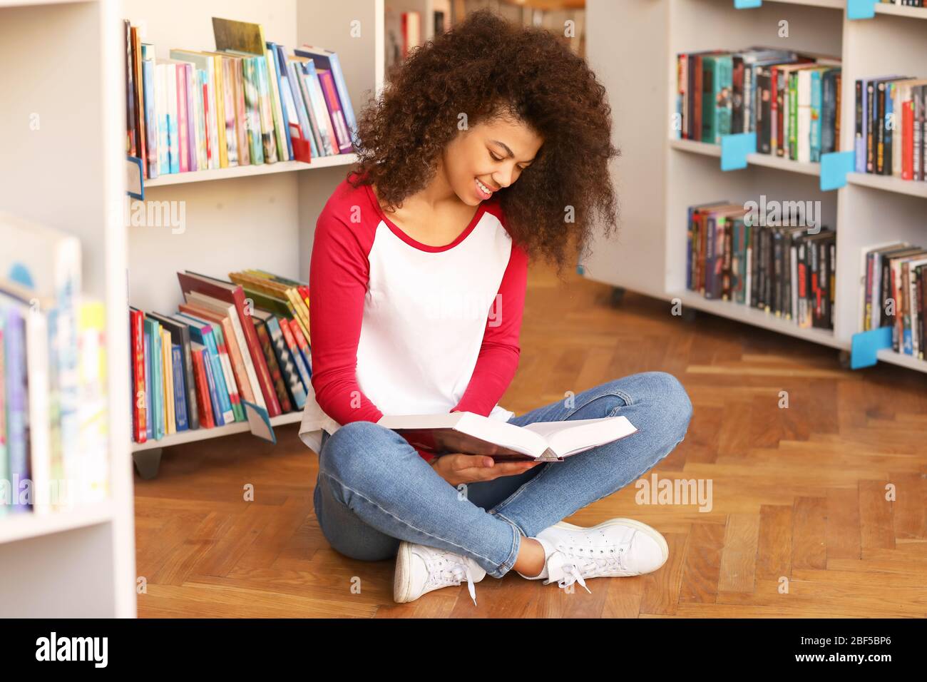 African-American student reading book while preparing for exam in ...