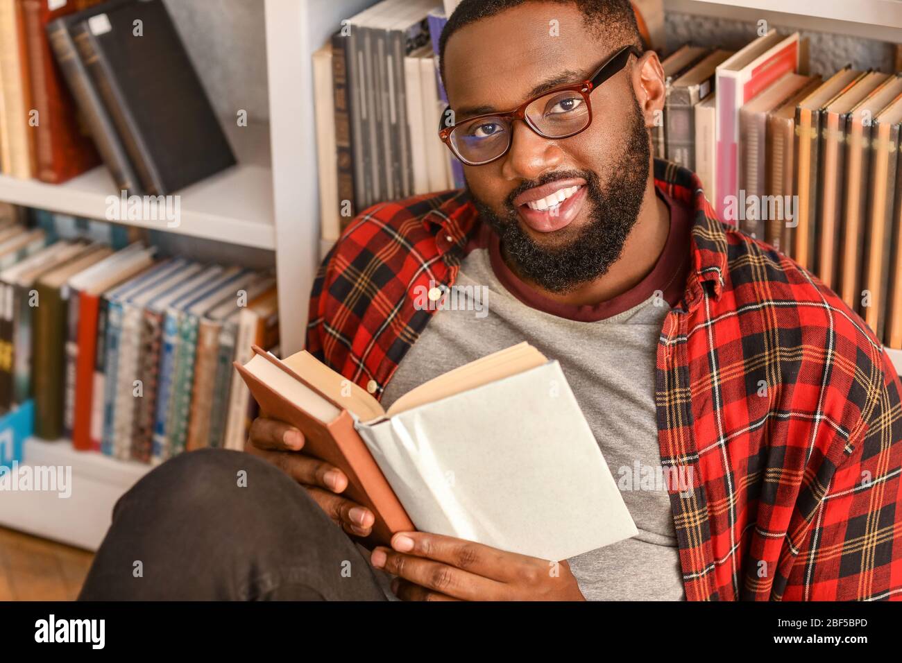 African-American student reading book while preparing for exam in ...