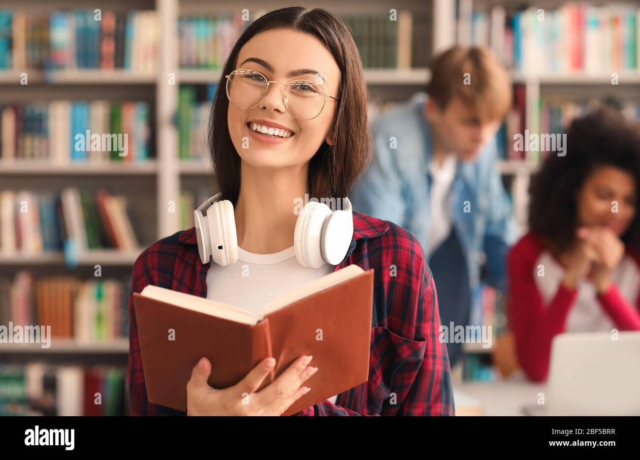 Female student reading book while preparing for exam in library Stock ...