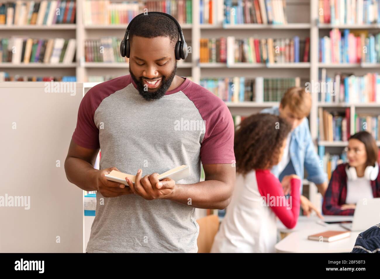 African-American student reading book while preparing for exam in ...