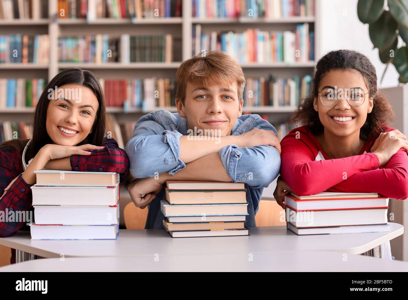 Young students with books in library Stock Photo - Alamy