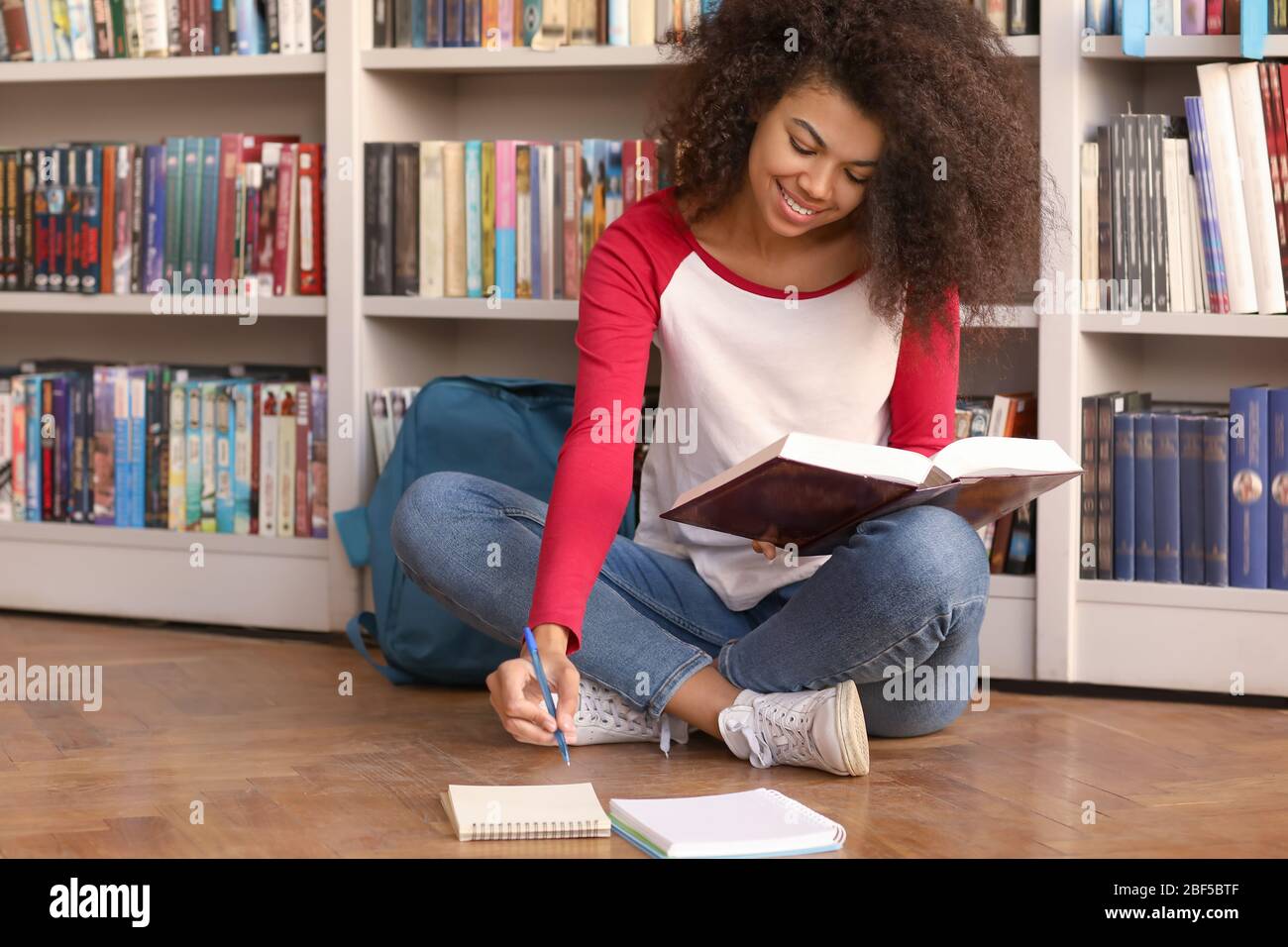 African-American student reading book while preparing for exam in ...
