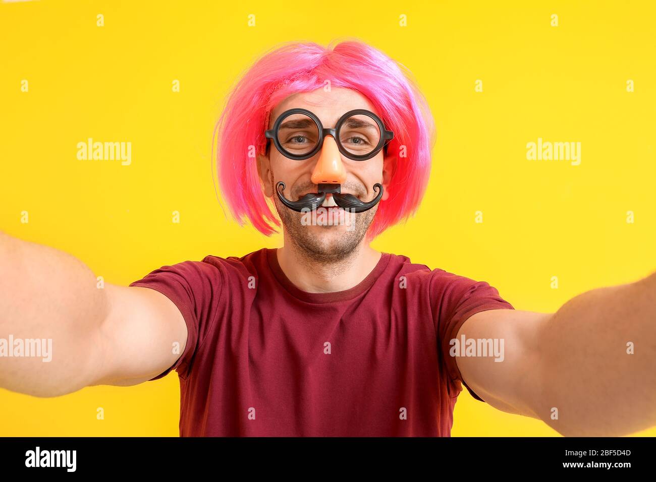 Man in funny disguise taking selfie on color background. April fools ...
