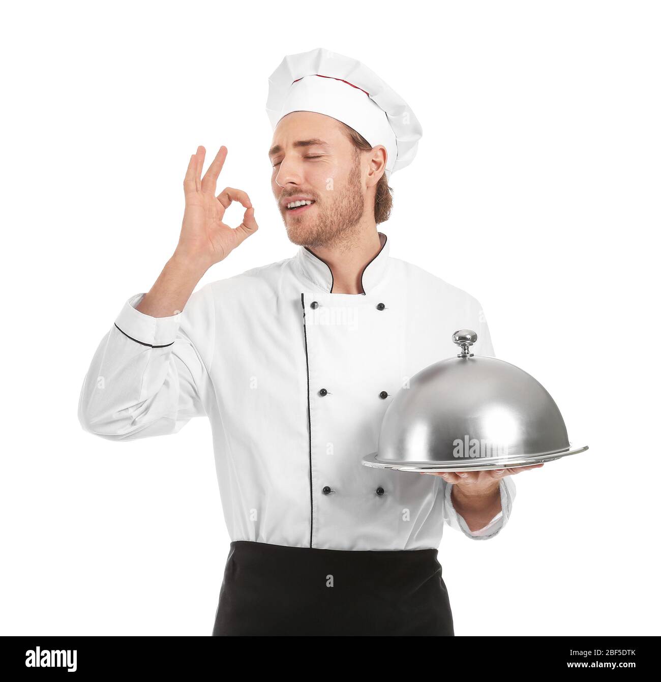 Happy male chef with tray and cloche showing OK gesture on white ...