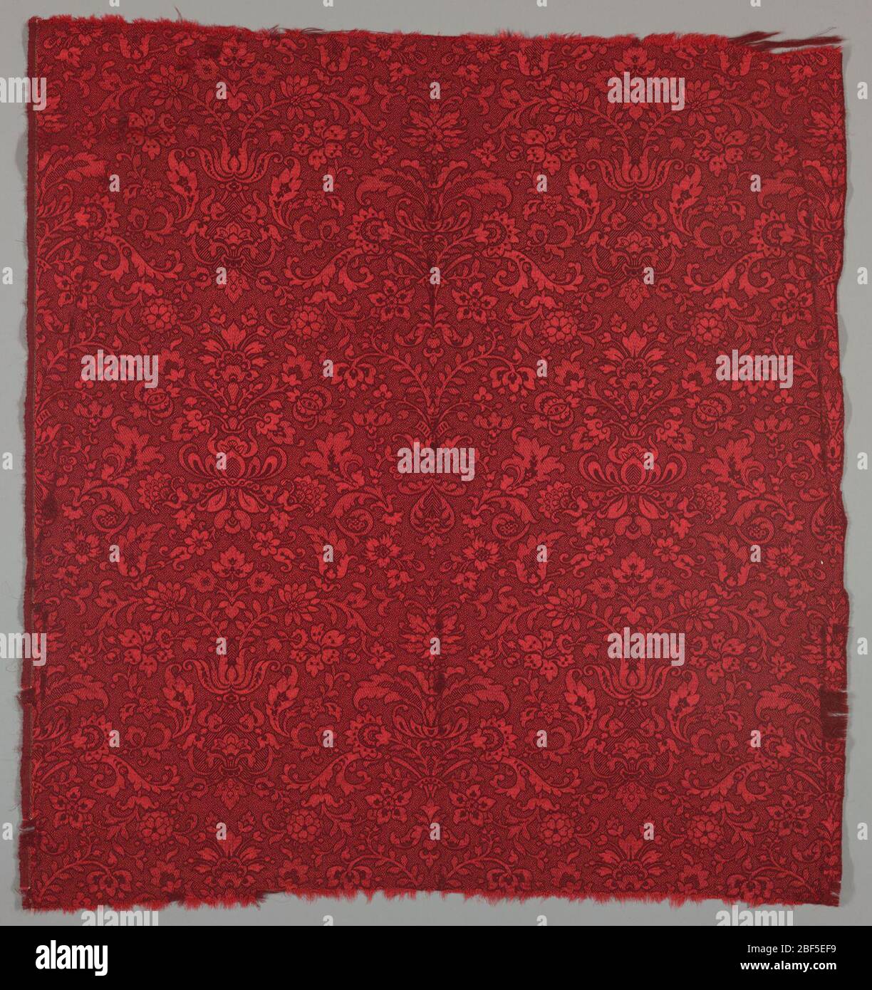 Textile. Orange silk warp and dark red wool weft. Scrolling symmetrical ...