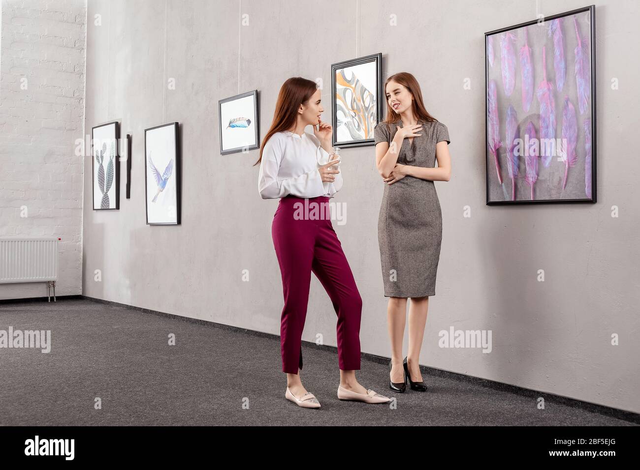 Young women at exhibition in modern art gallery Stock Photo - Alamy
