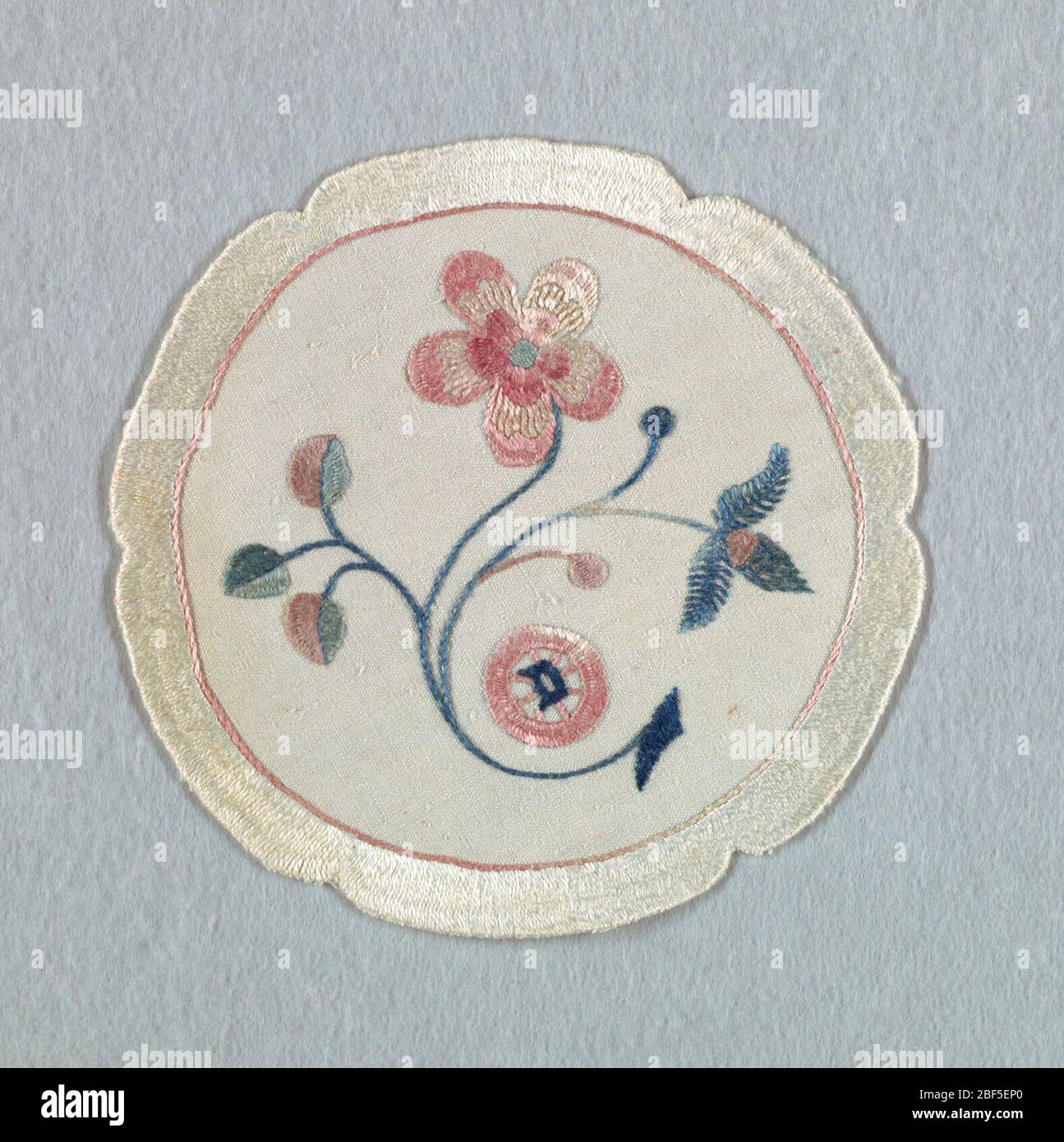 Doily. Stem with two blossoms in muted colors within a notched circle ...