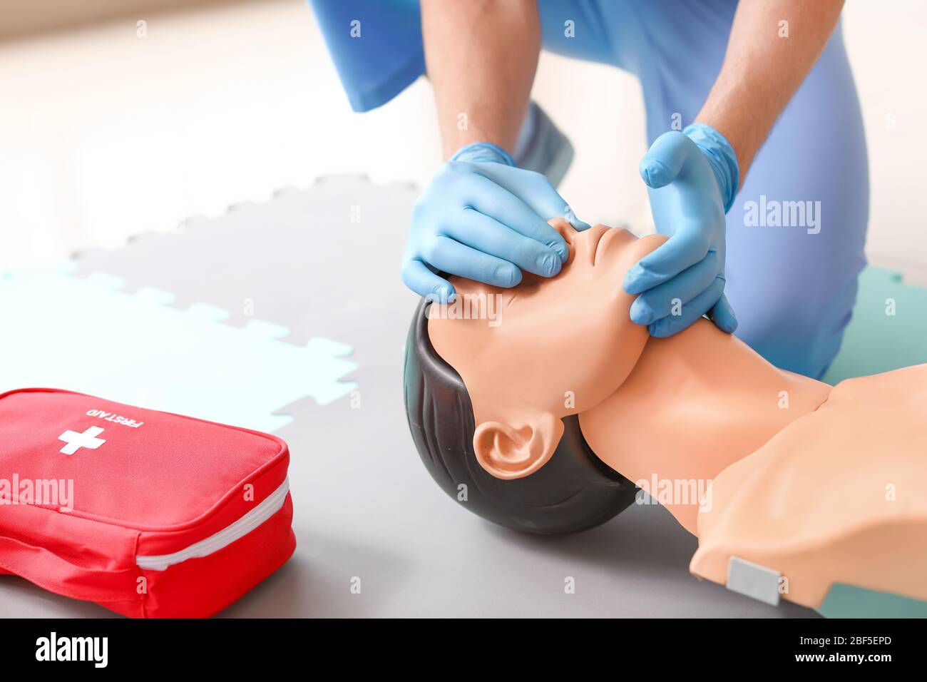 Instructor demonstrating CPR on mannequin at first aid training course ...