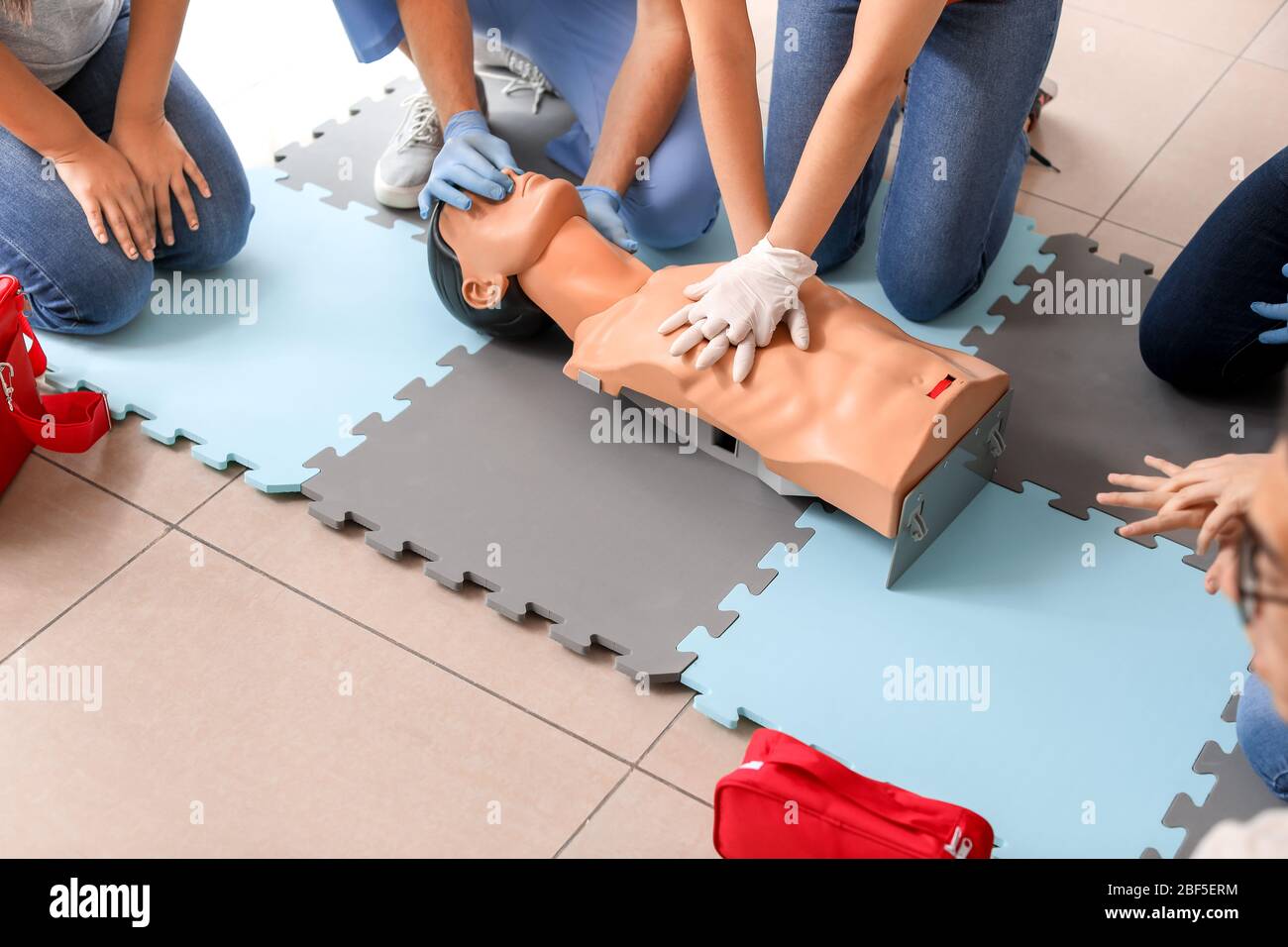 Instructors demonstrating CPR on mannequin at first aid training course ...