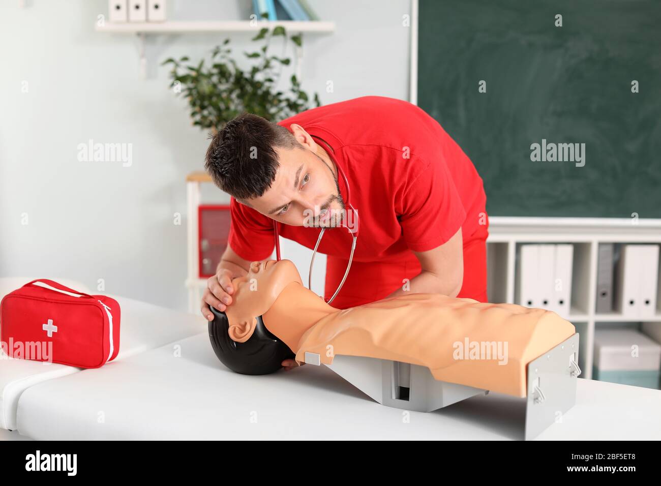 Instructor demonstrating CPR on mannequin at first aid training course ...