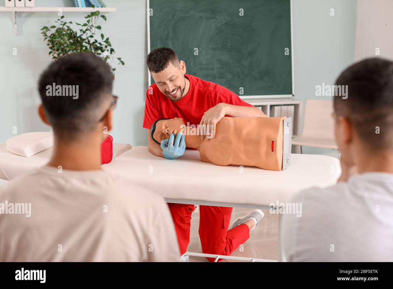 Instructor demonstrating CPR on mannequin at first aid training course ...