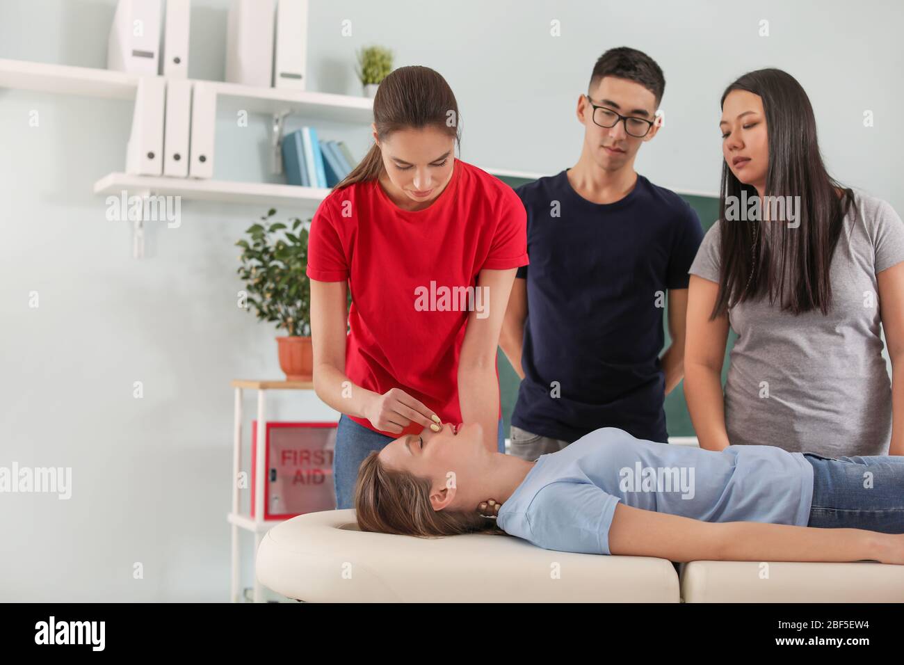 Instructor demonstrating CPR on woman at first aid training course ...