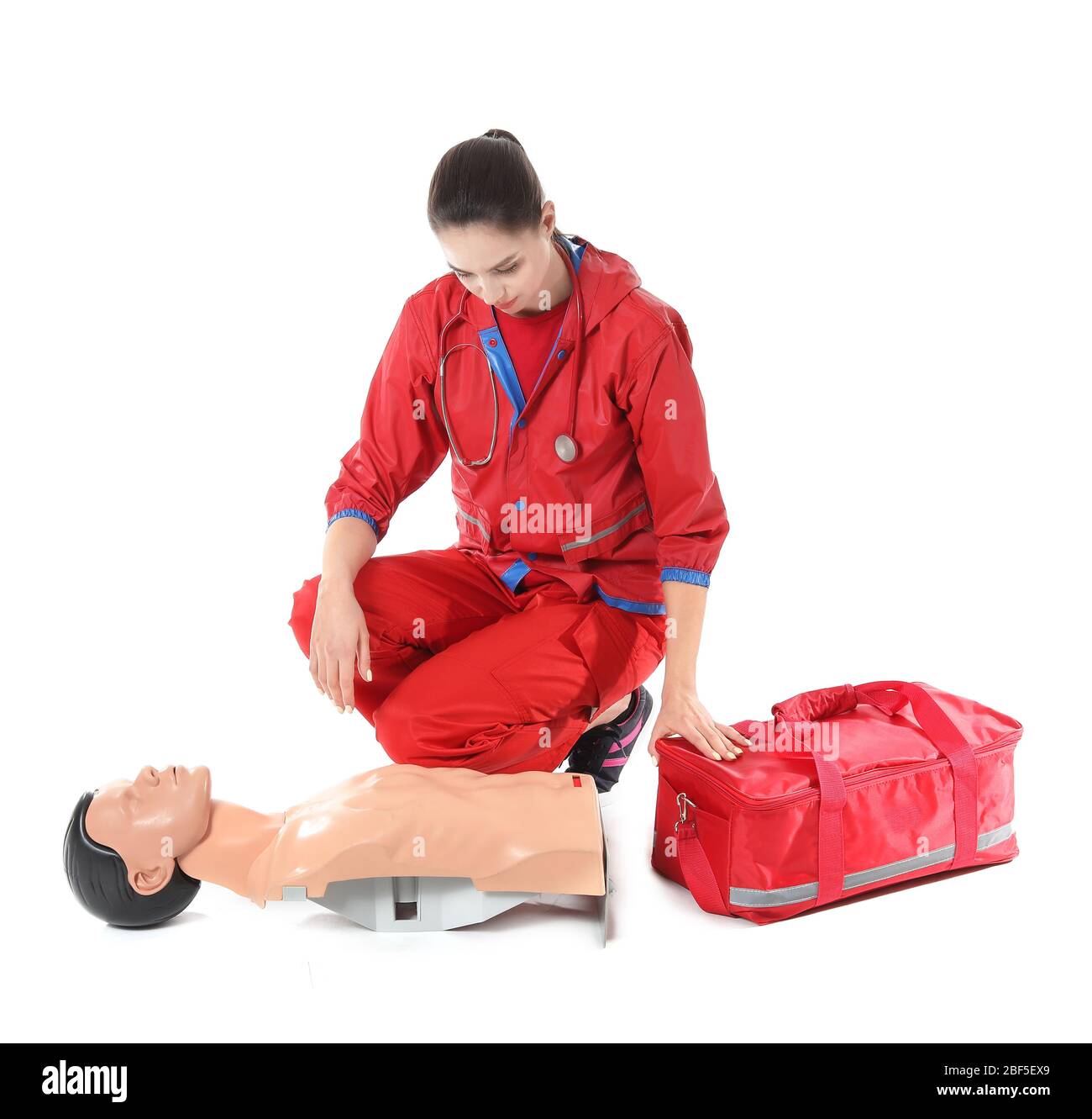 Female paramedic with mannequin and bag on white background Stock Photo ...